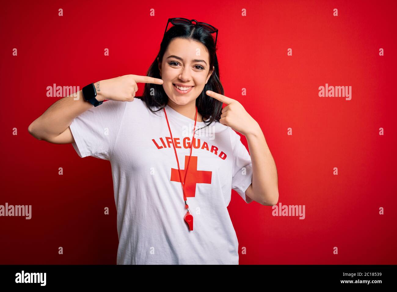 Young lifeguard woman wearing secury guard equipent over red background ...