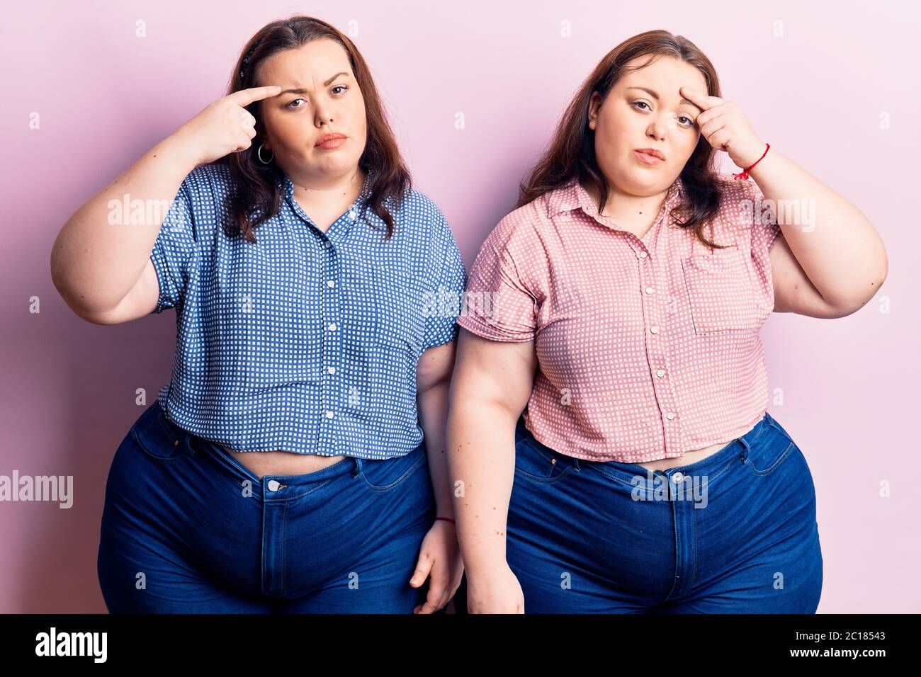 Young plus size twins wearing casual clothes pointing unhappy to pimple ...