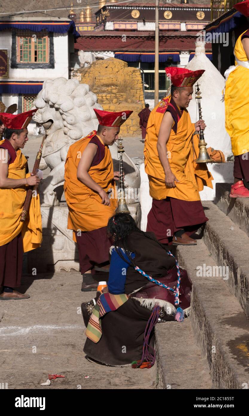A woman watches the procession of the monks, Tsurphu monastery festival ...