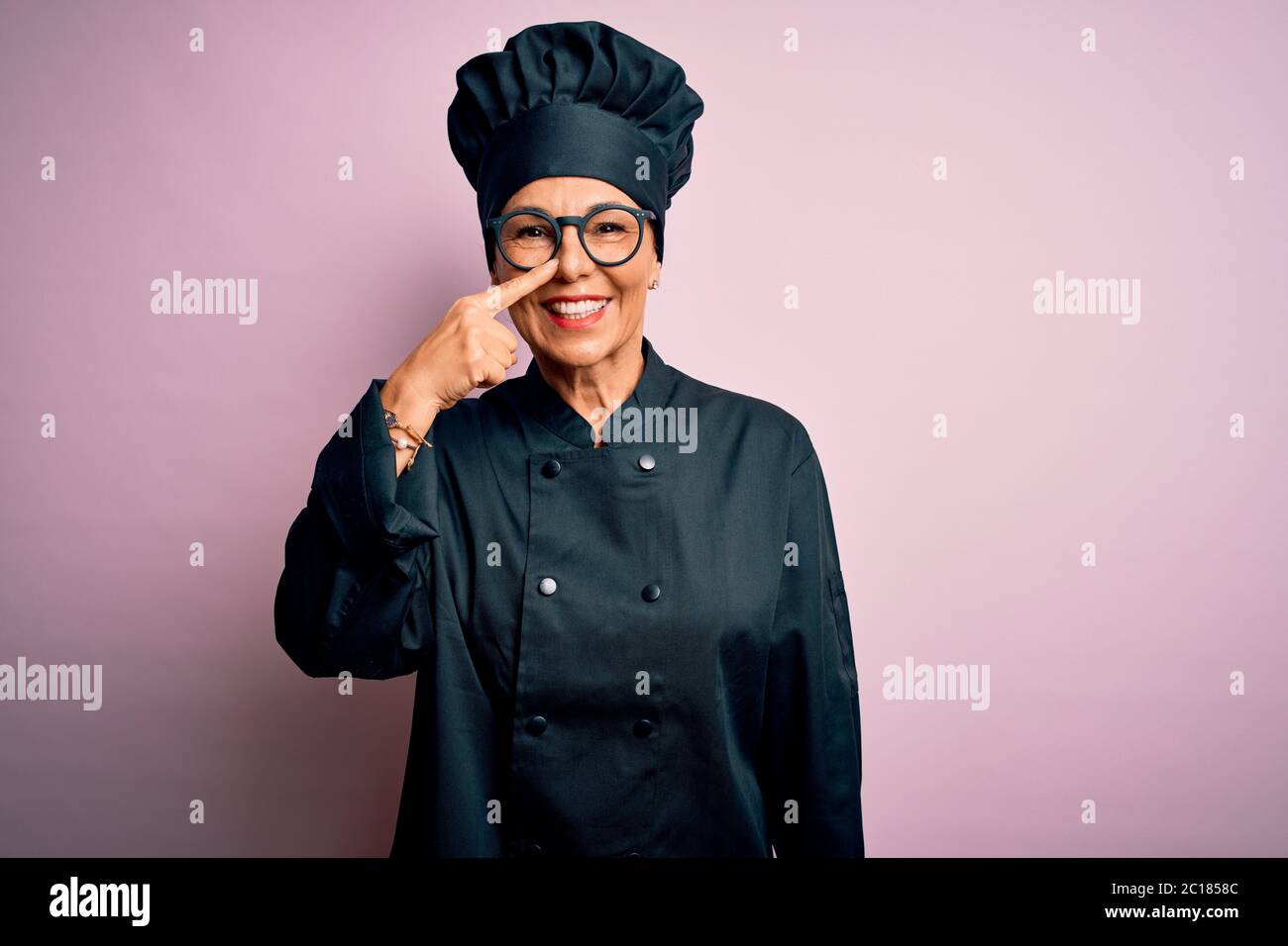 Middle age brunette chef woman wearing cooker uniform and hat over ...
