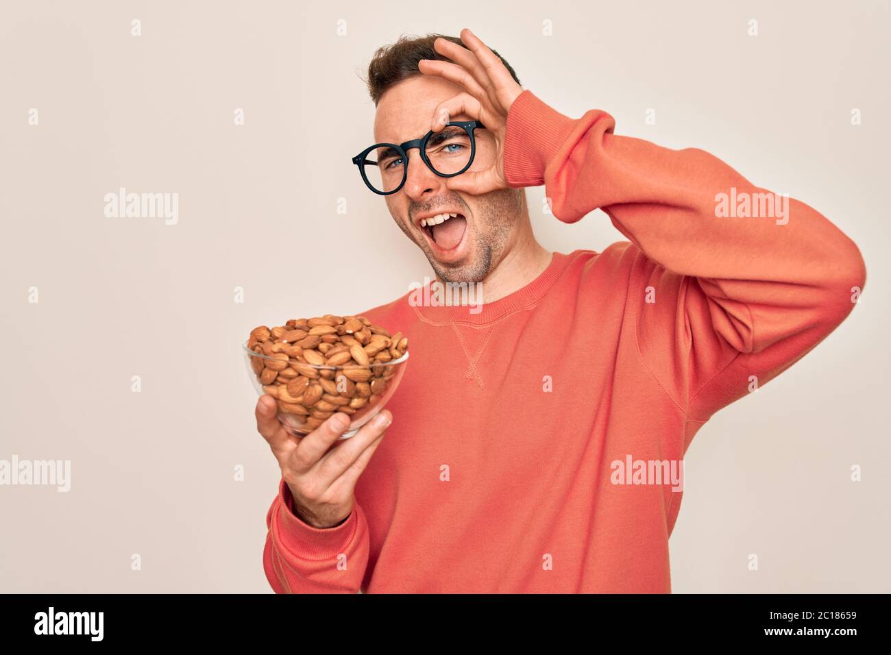 Handsome man with blue eyes holding bowl with healthy almonds snack ...