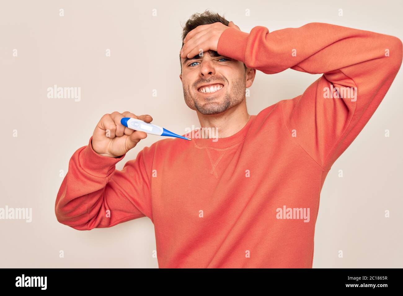 Young handsome man with blue eyes measuring temperature using digital ...