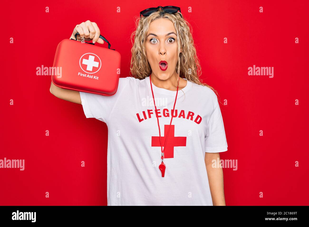 Beautiful blonde lifeguard woman wearing t-shirt with red cross and ...