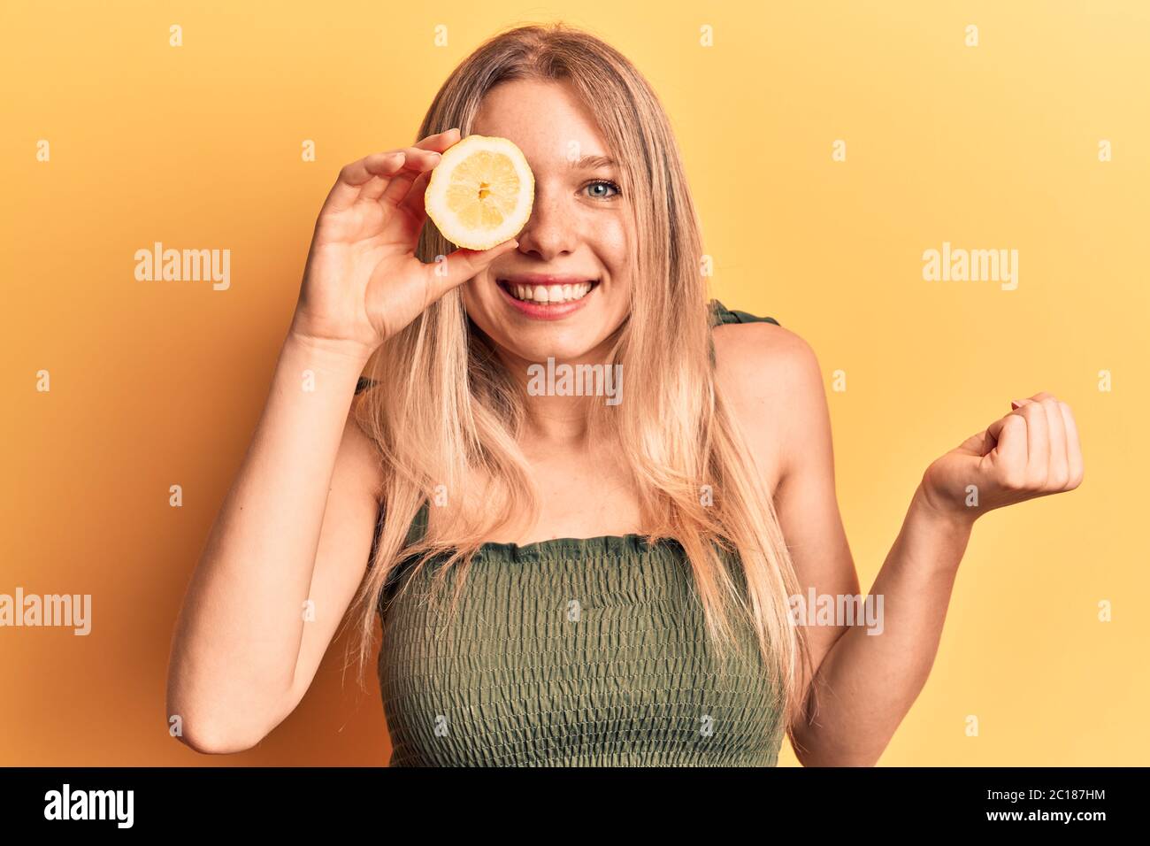 Young blonde woman holding lemon screaming proud, celebrating victory ...