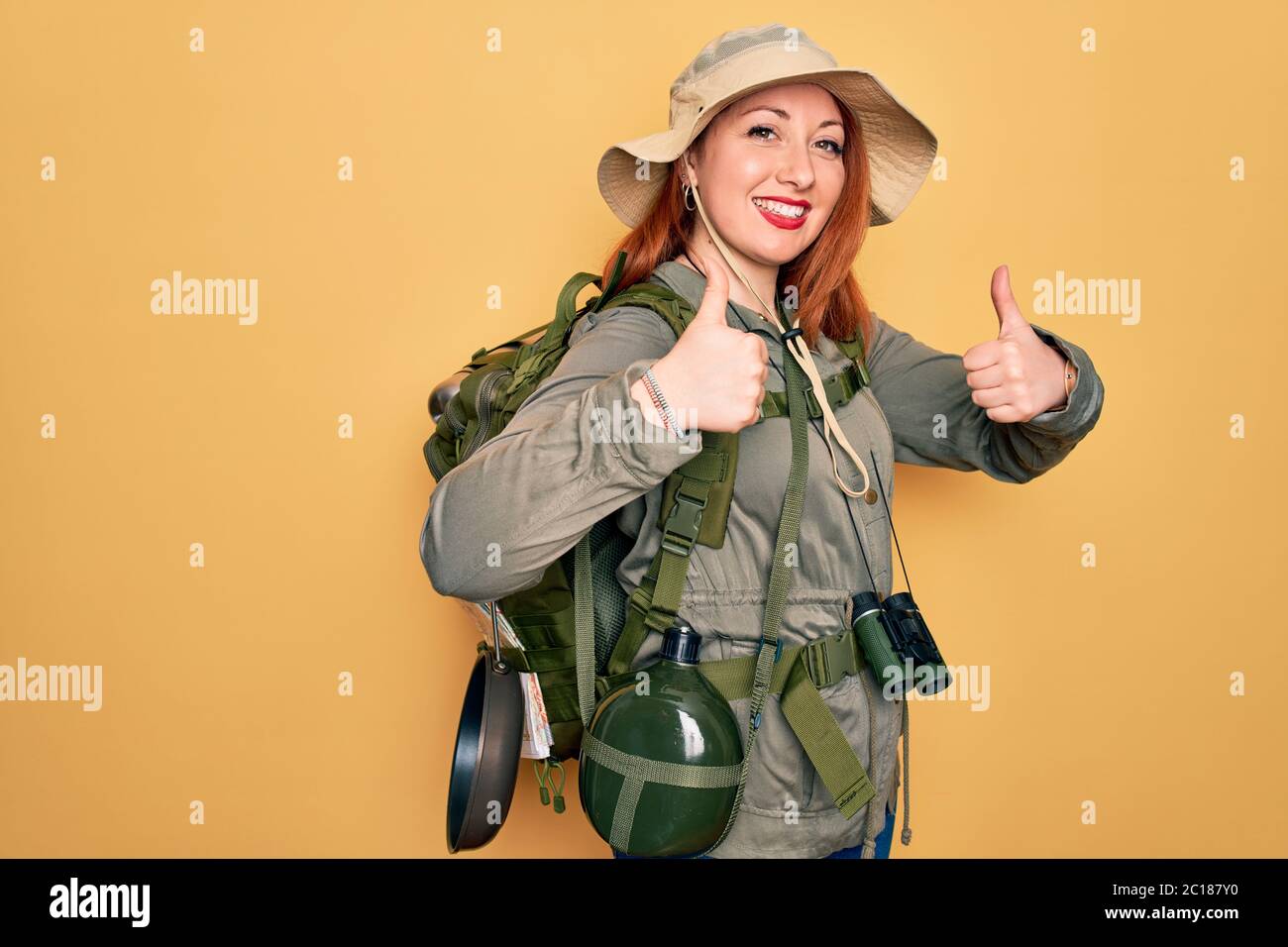 Young redhead backpacker woman hiking wearing backpack and hat over ...