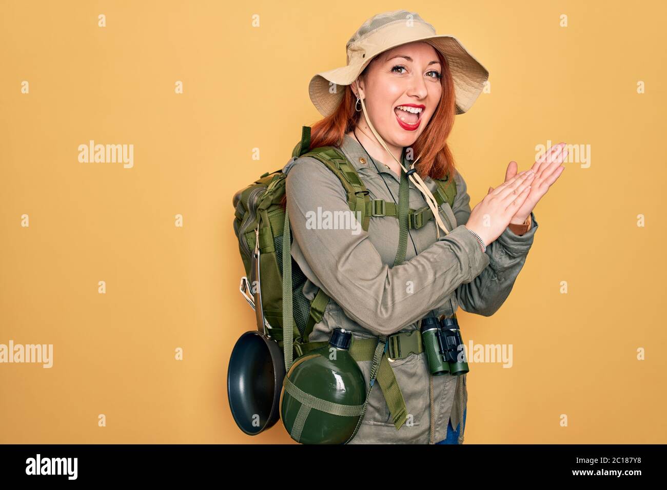 Young redhead backpacker woman hiking wearing backpack and hat over ...