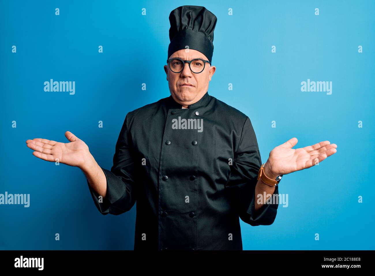Middle age handsome grey-haired chef man wearing cooker uniform and hat ...