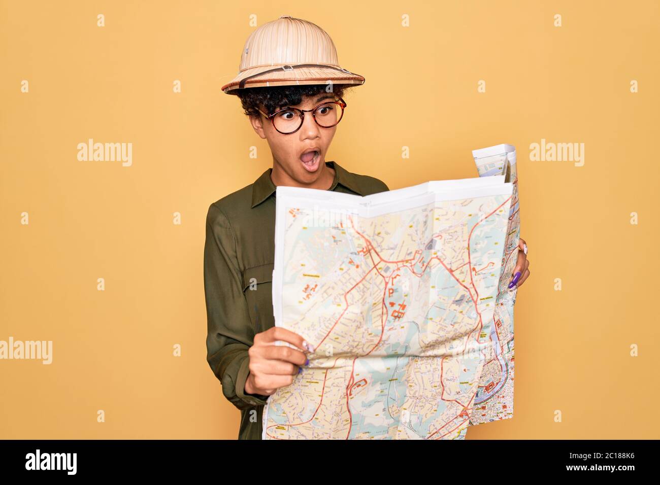 Beautiful african american explorer woman wearing hat holding city map ...