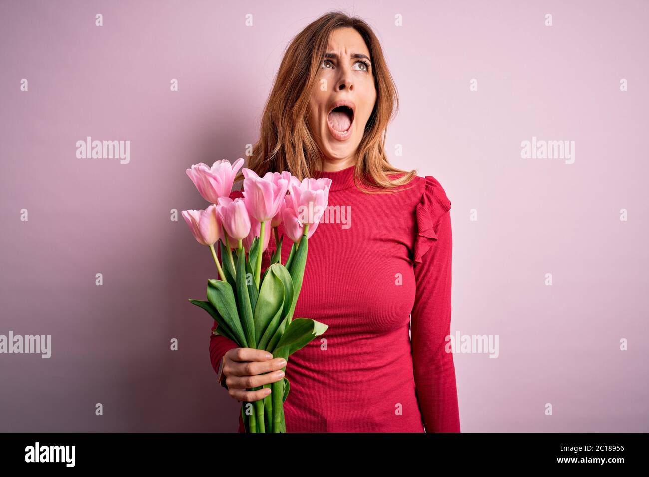 Young beautiful brunette woman holding bouquet of pink tulips over ...