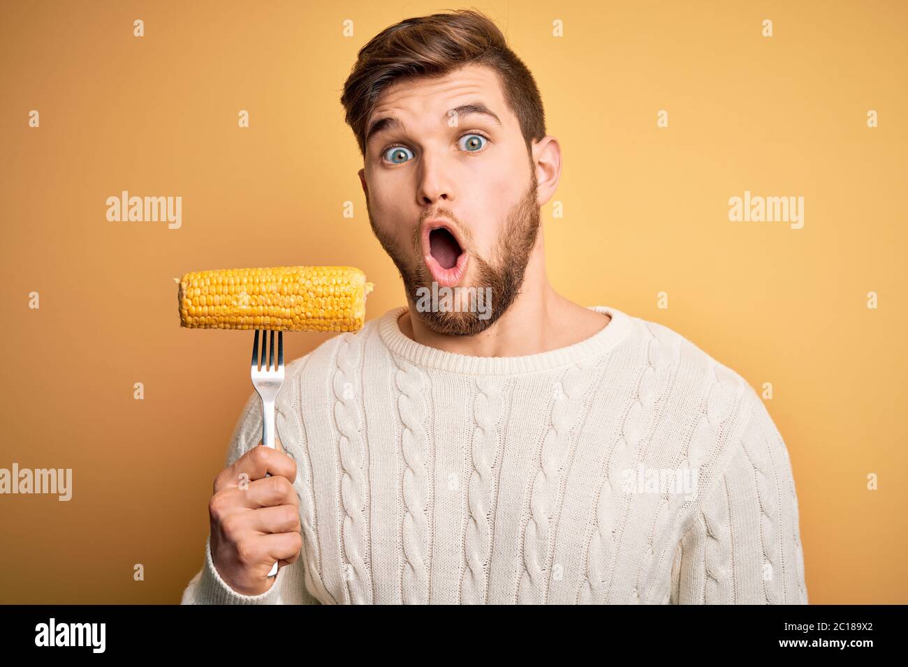 Young blond vegetarian man with beard and blue eyes holding fork with ...