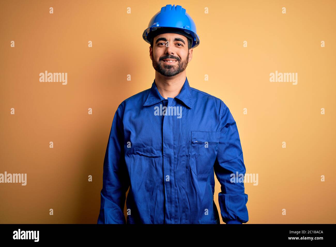 Mechanic man with beard wearing blue uniform and safety helmet over ...