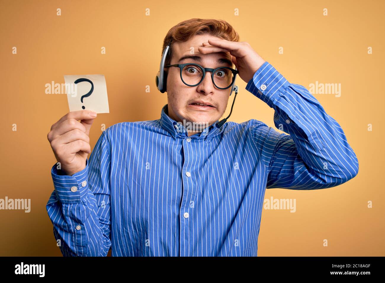 Redhead call center agent man working using headset holding reminder ...