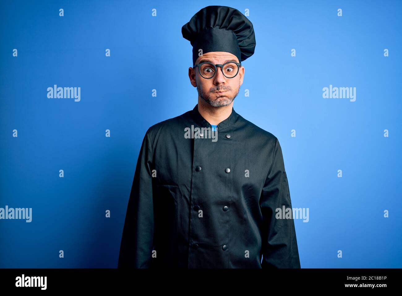 Young handsome chef man wearing cooker uniform and hat over isolated ...