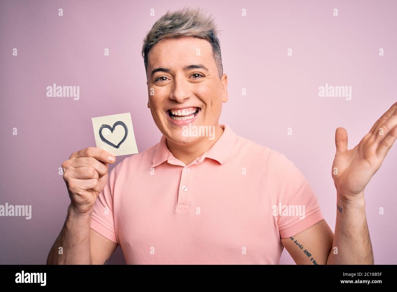 Young modern romantic man holding heart shape drawing over isolated ...