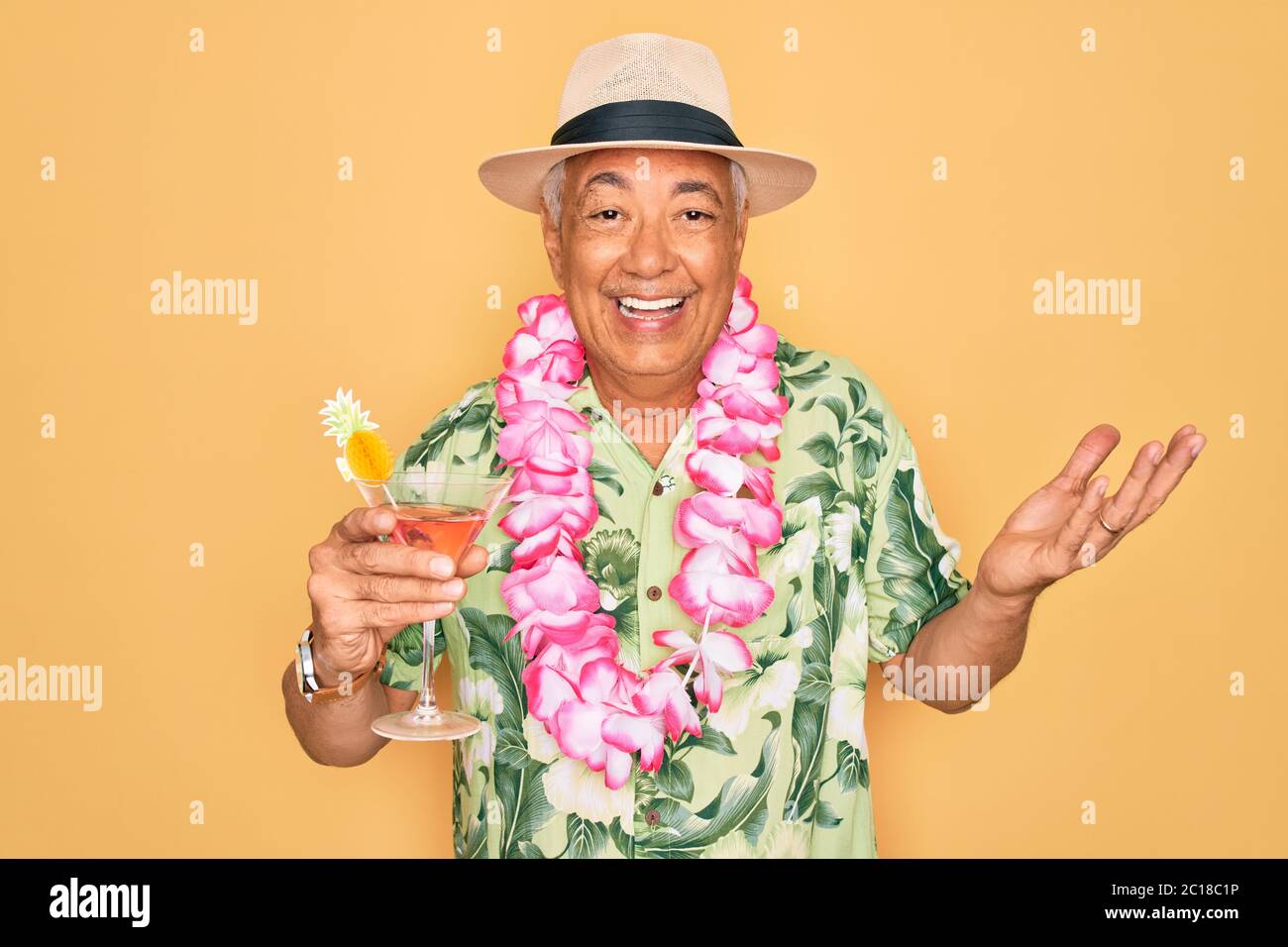 Middle age senior grey-haired man wearing summer hat and hawaiian lei ...