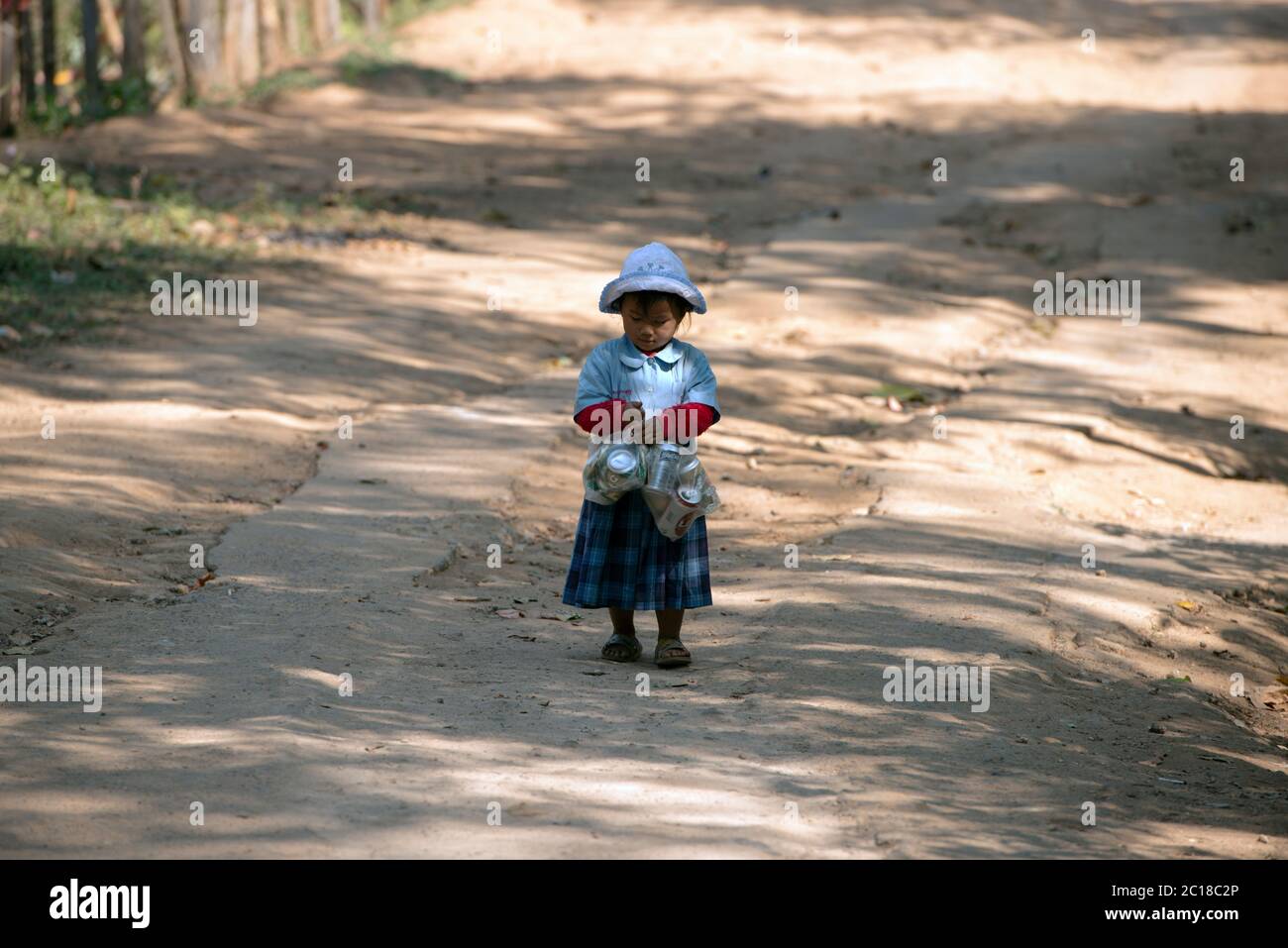 A young, indigenous, ethnic Shan girl picking up rubbish/trash/garbage ...