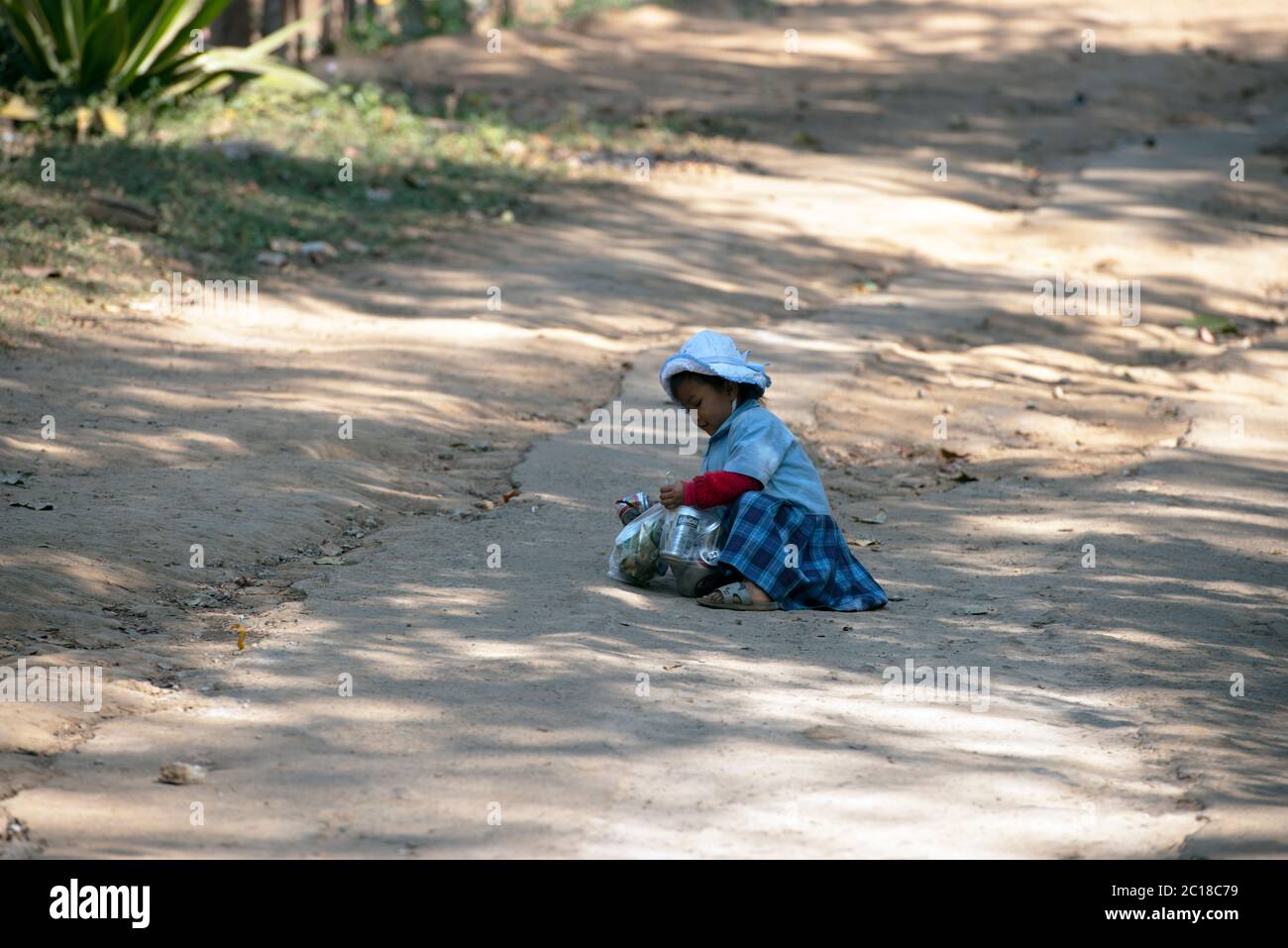 A young, indigenous, ethnic Shan girl picking up rubbish/trash/garbage ...