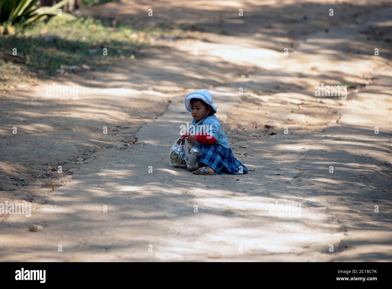 A young, indigenous, ethnic Shan girl picking up rubbish/trash/garbage ...
