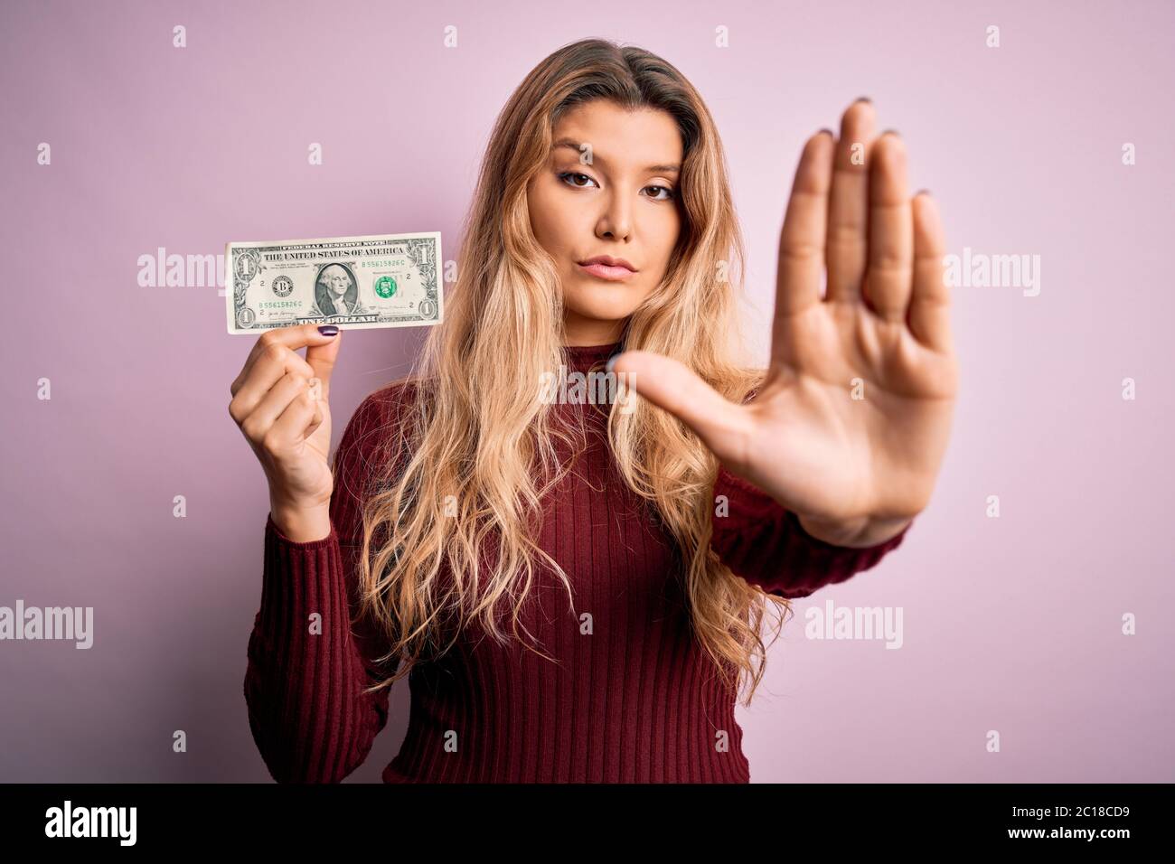 Young beautiful blonde woman holding one dollar banknote over isolated ...