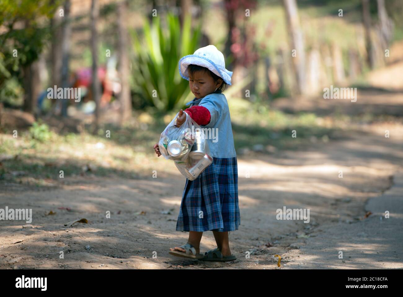A young, indigenous, ethnic Shan girl picking up rubbish/trash/garbage ...