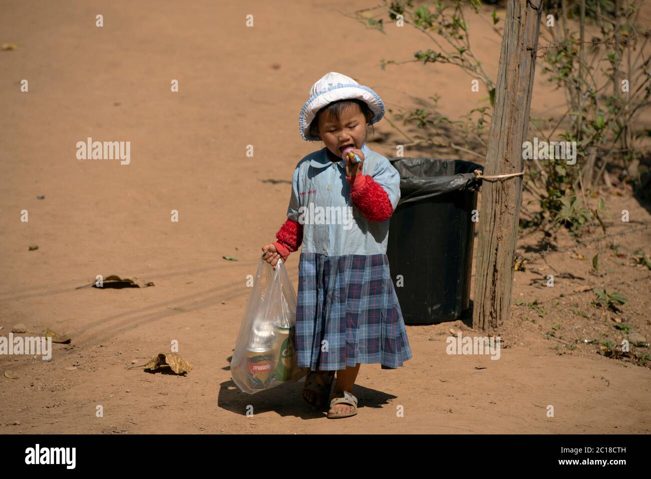 A young, indigenous, ethnic Shan girl picking up rubbish/trash/garbage ...