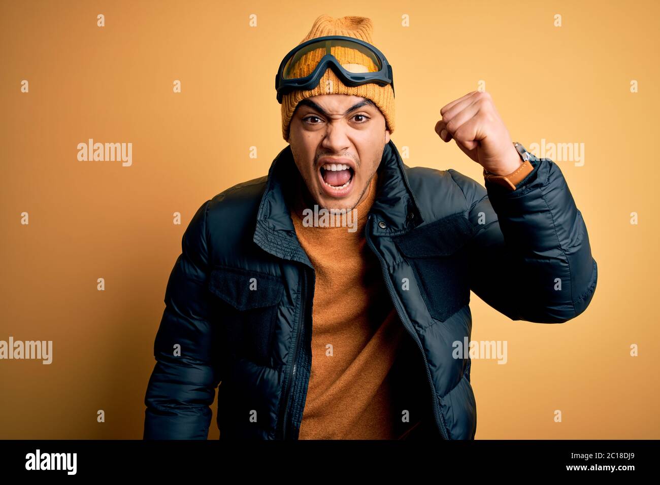 Young brazilian skier man wearing snow sportswear and ski goggles over ...