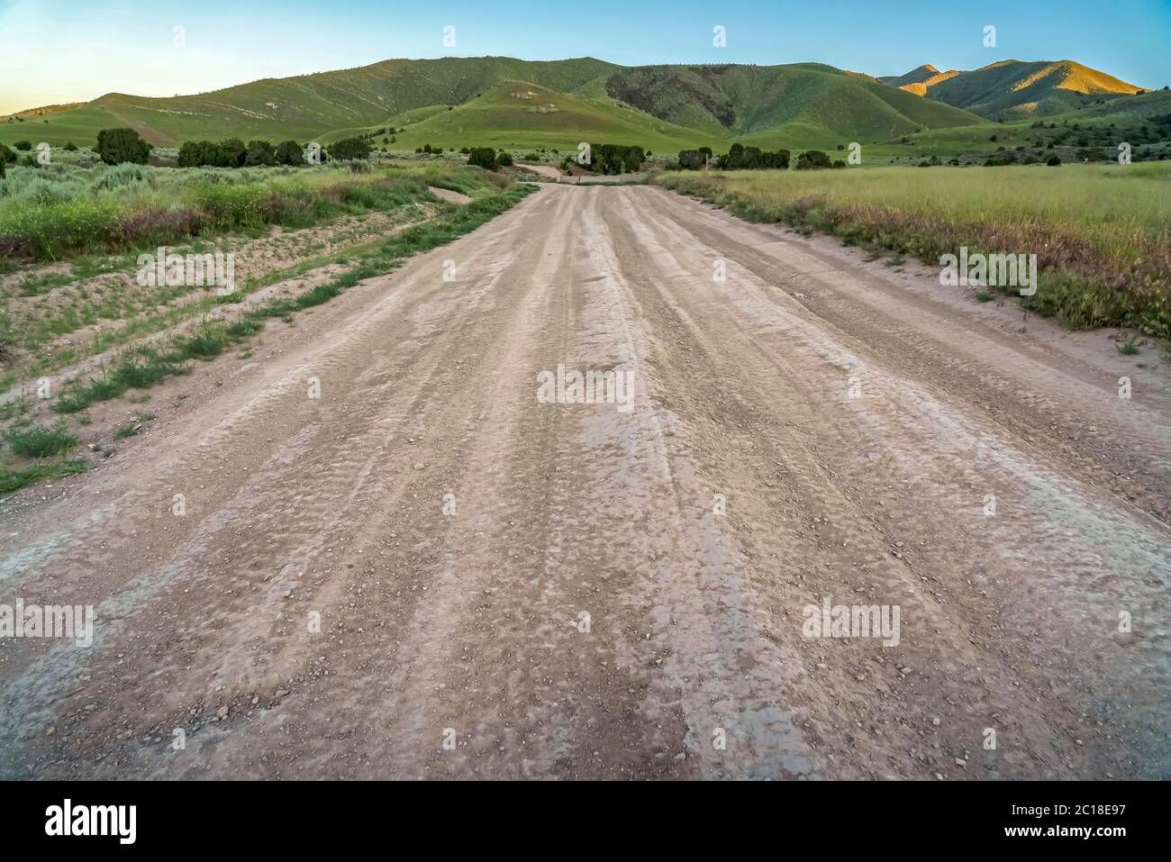 Rough road on a scenic hill landscape blanketed with lush greenery and ...