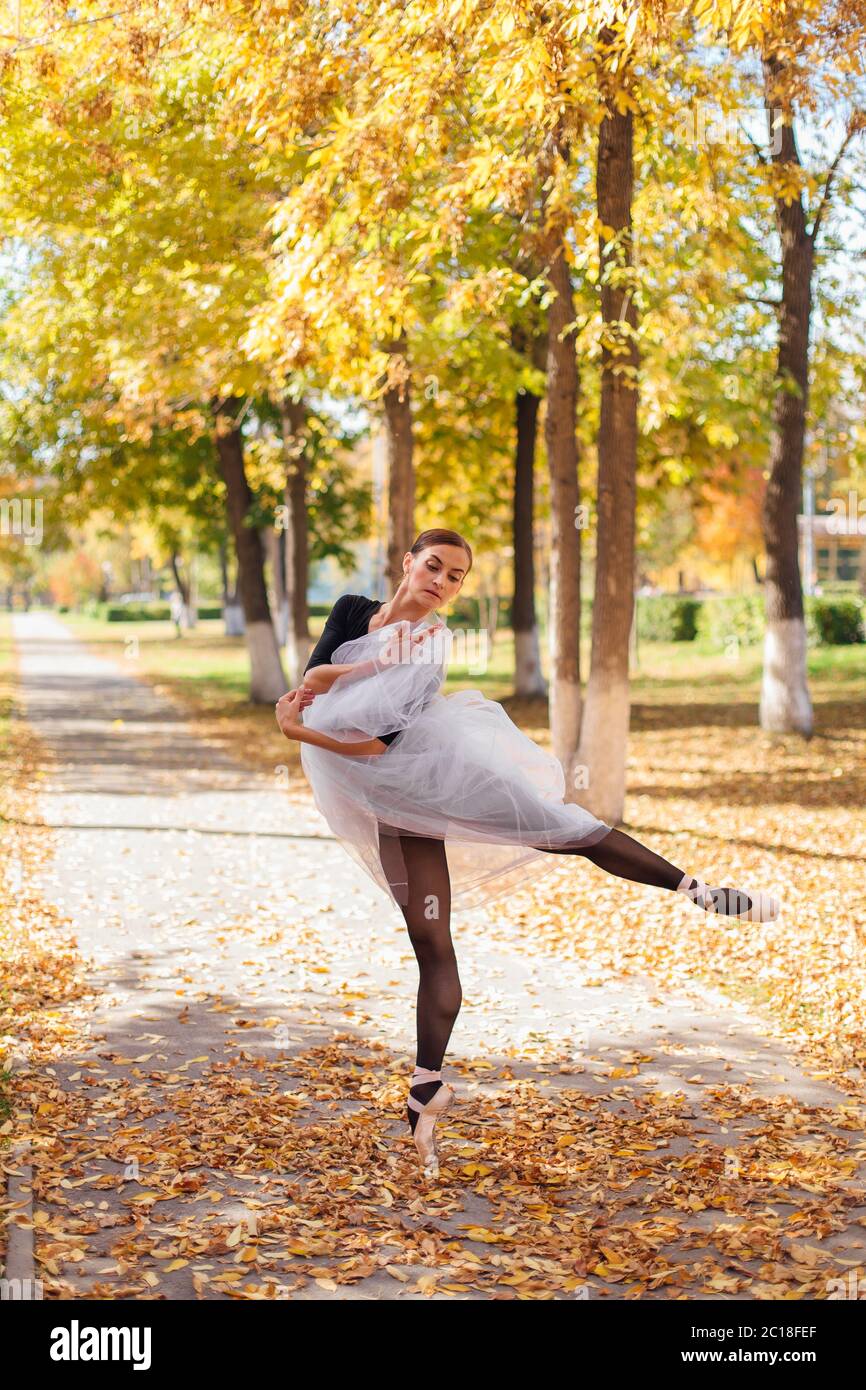 Woman ballerina in a white ballet skirt dancing in pointe shoes in a ...