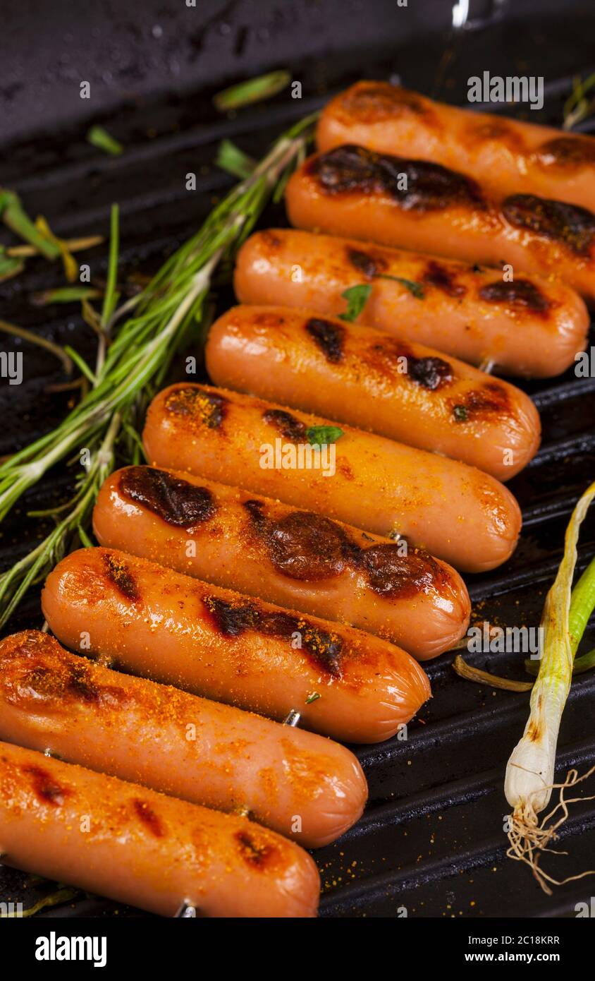 Fried sausages with herbs, spices and vegetables in a pan close up ...