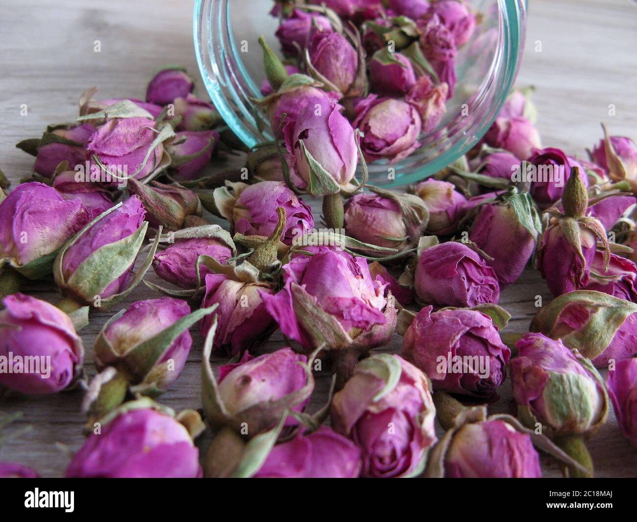 Pink Dried Rose Buds (Herbal Tea) in glass bottle on wooden background ...