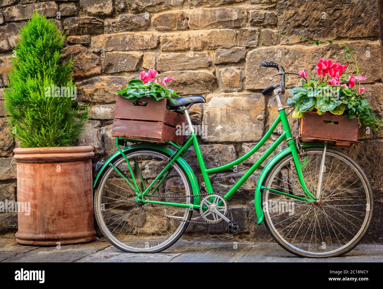 Green bicycle with boxes with flowers next to a stone wall in Florence ...