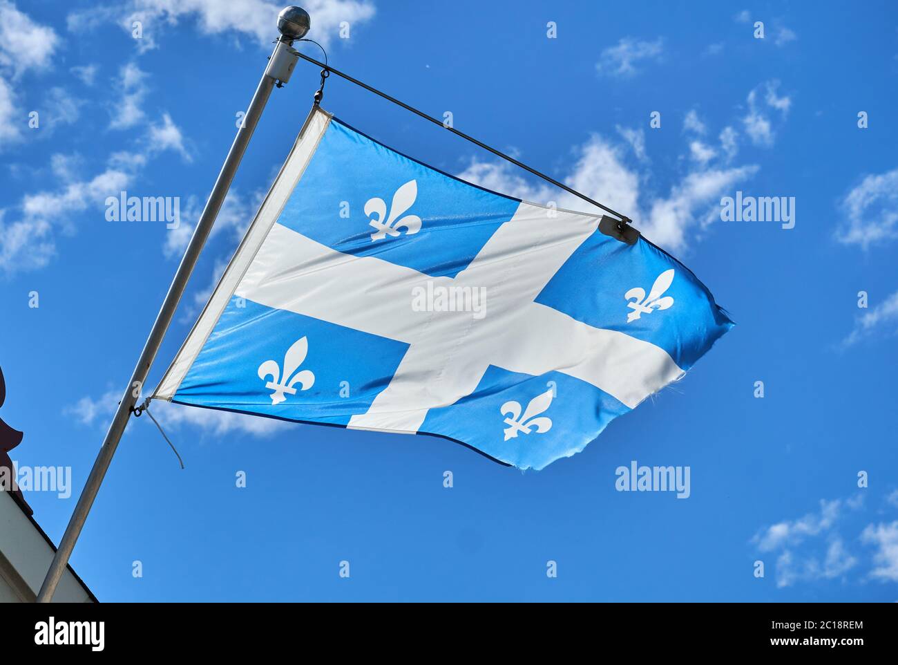 The waving flag of Quebec over a blue sky background. The flag of ...