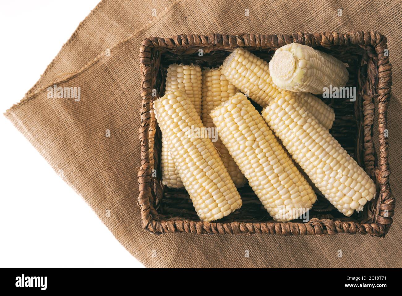 Corn in a basket. Raw organic corn in wicker basket close up isolated ...