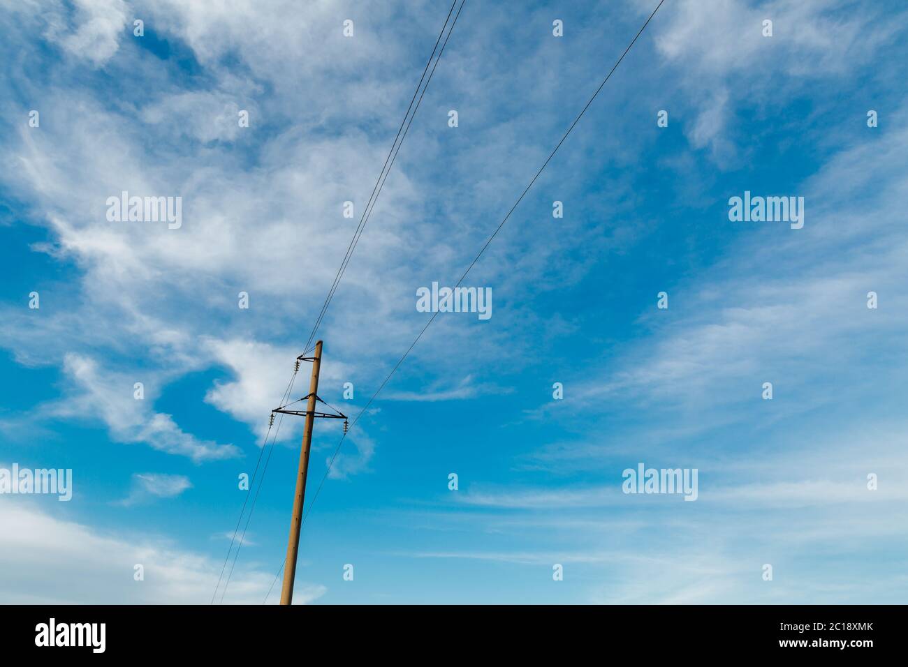 Power line post with electricity cables against a clear sky with white ...