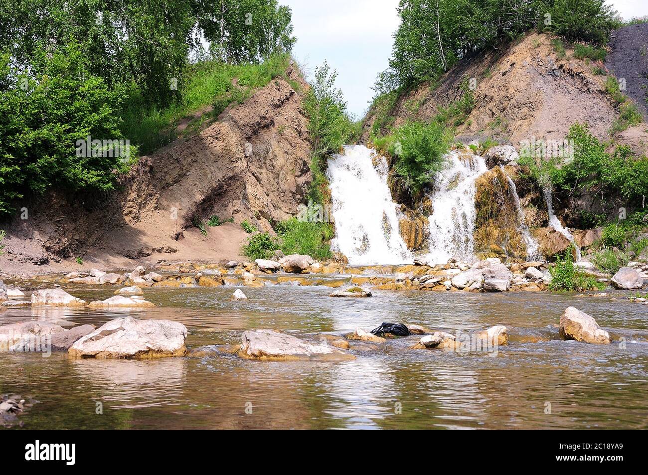 A picturesque waterfall with rocky cliffs and a shallow river flowing ...