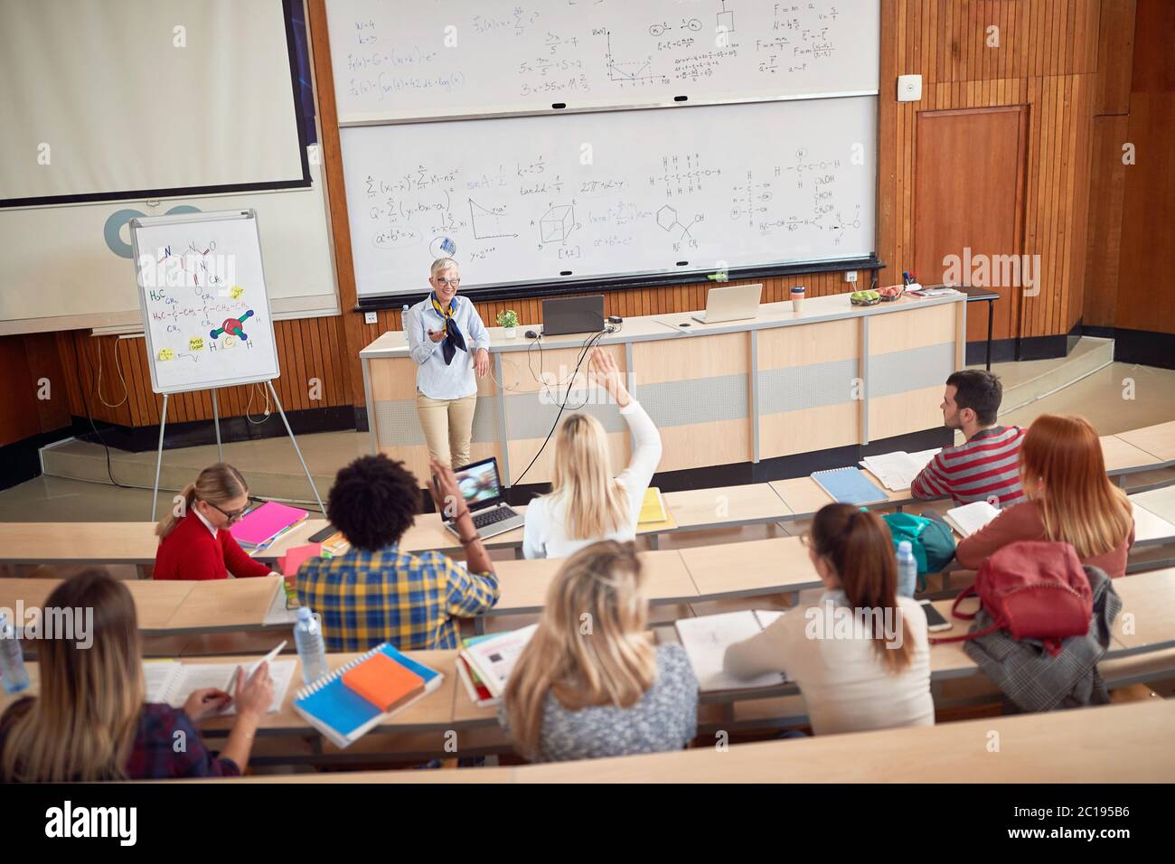 Students on a lecture in amphitheater answering professor's question ...