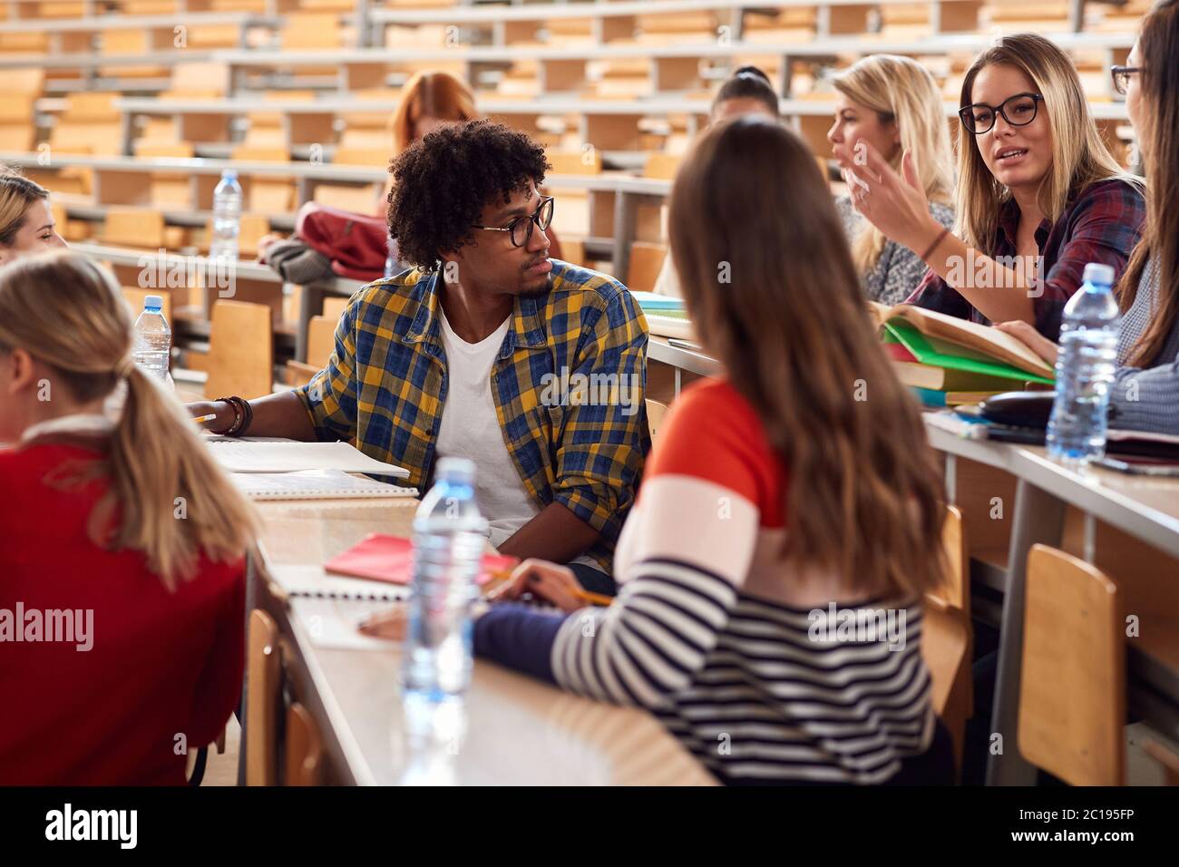 Young freshman students branstorming and comparing notes in ...