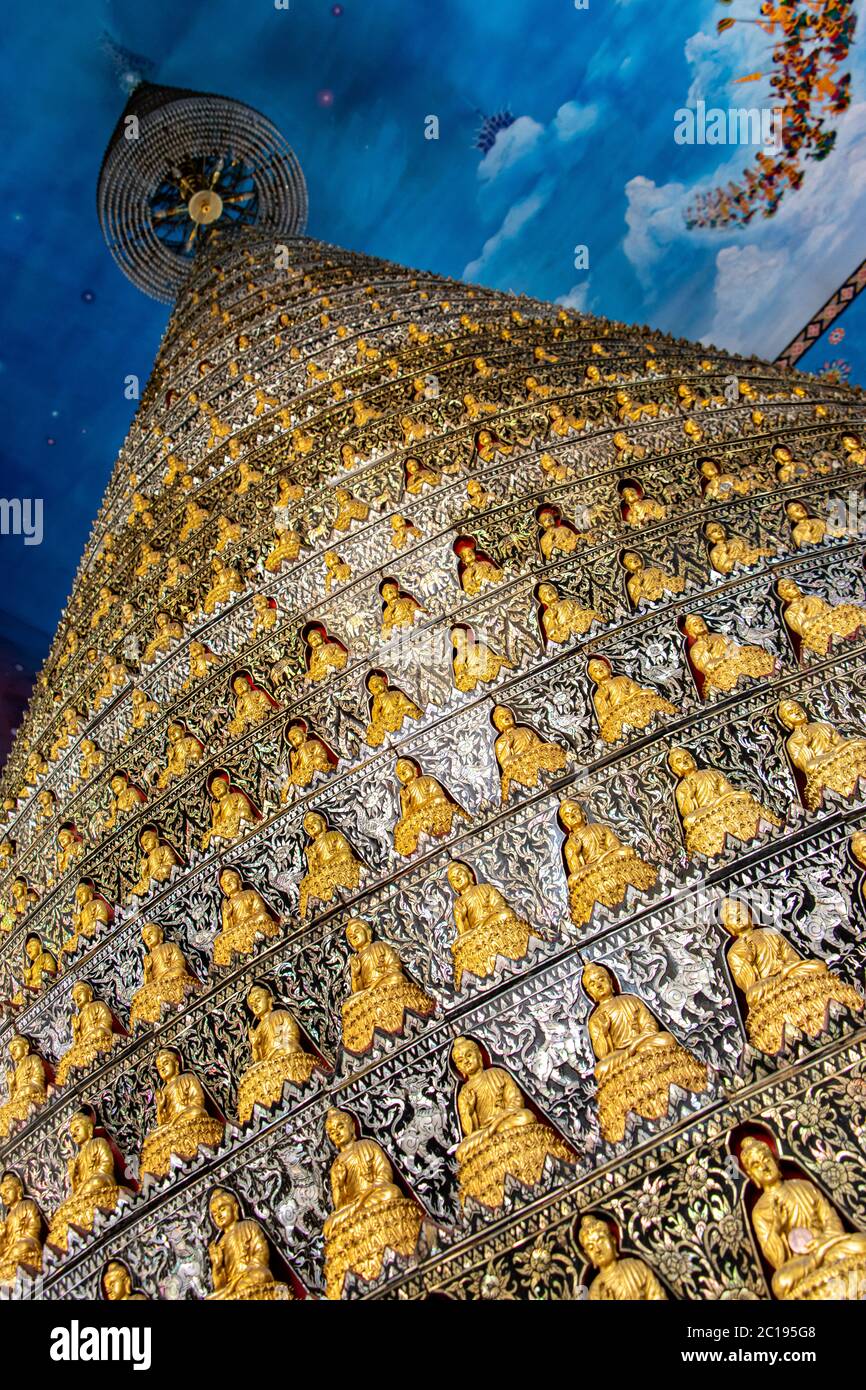 A pyramid with gilded Buddha figures rises to the ceiling of a Buddhist ...