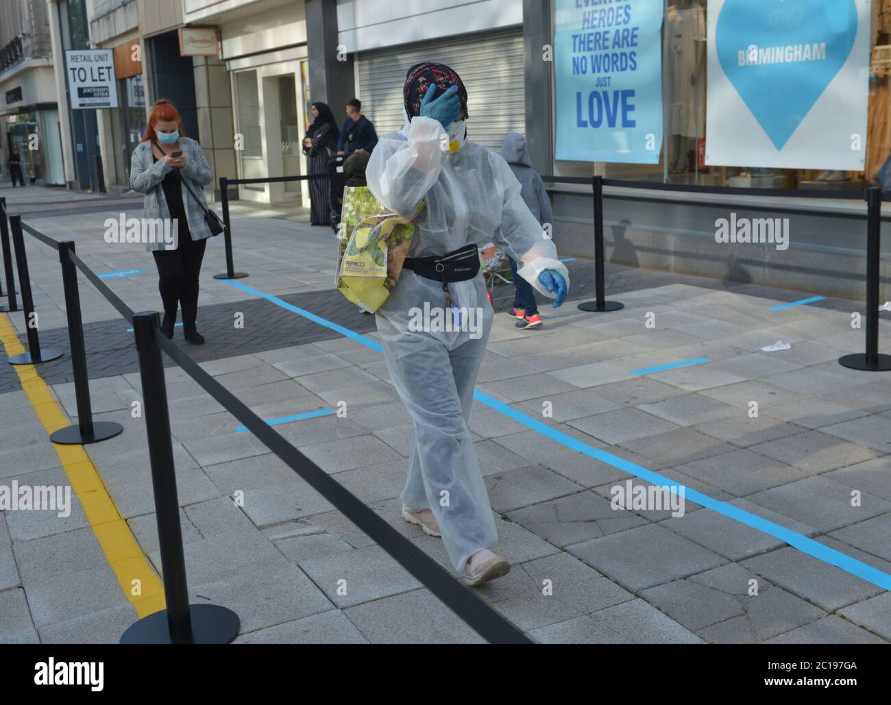 A customer dressed in personal protective equipment (PPE) in line to ...