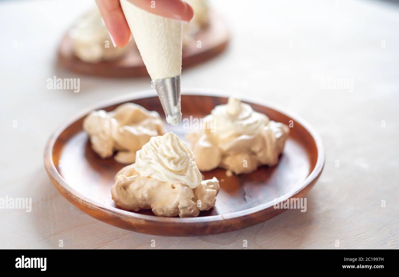 , decorating the meringue with cream from the culinary bag Stock Photo ...