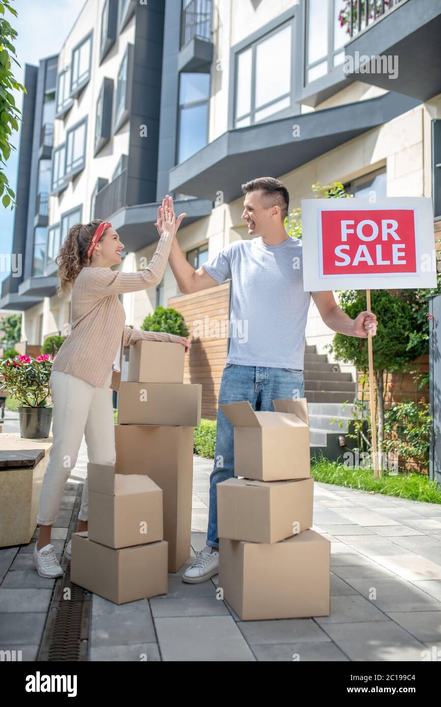 Smiling happy couple ready for moving to a new apartment and doing high ...