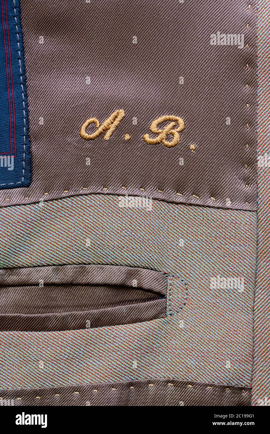 Initials embroidered inside a bespoke garment in yellow thread above an ...