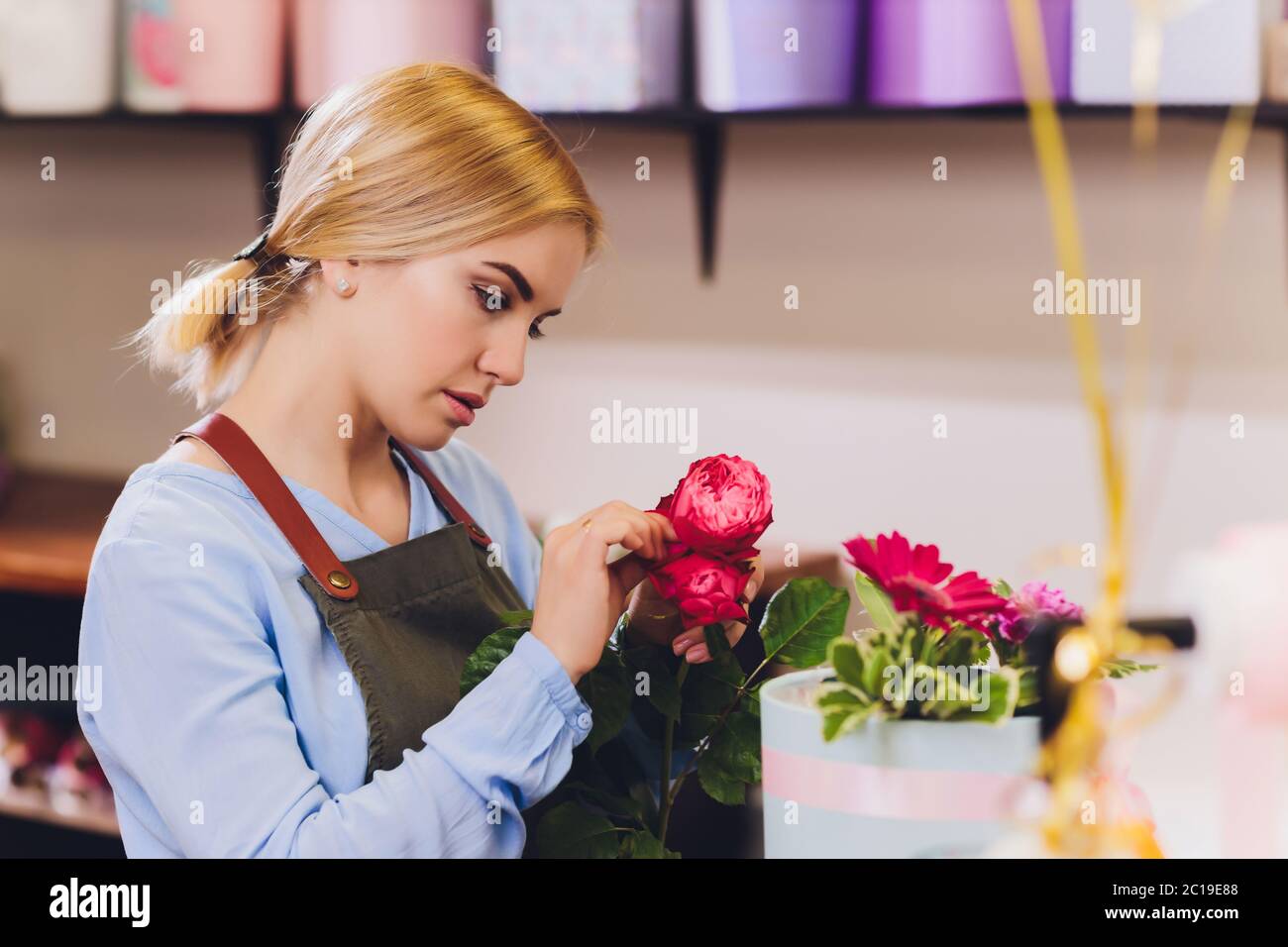 Female sales assistant working as florist and holding bouquet with ...