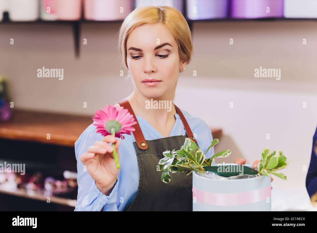 Female sales assistant working as florist and holding bouquet with ...
