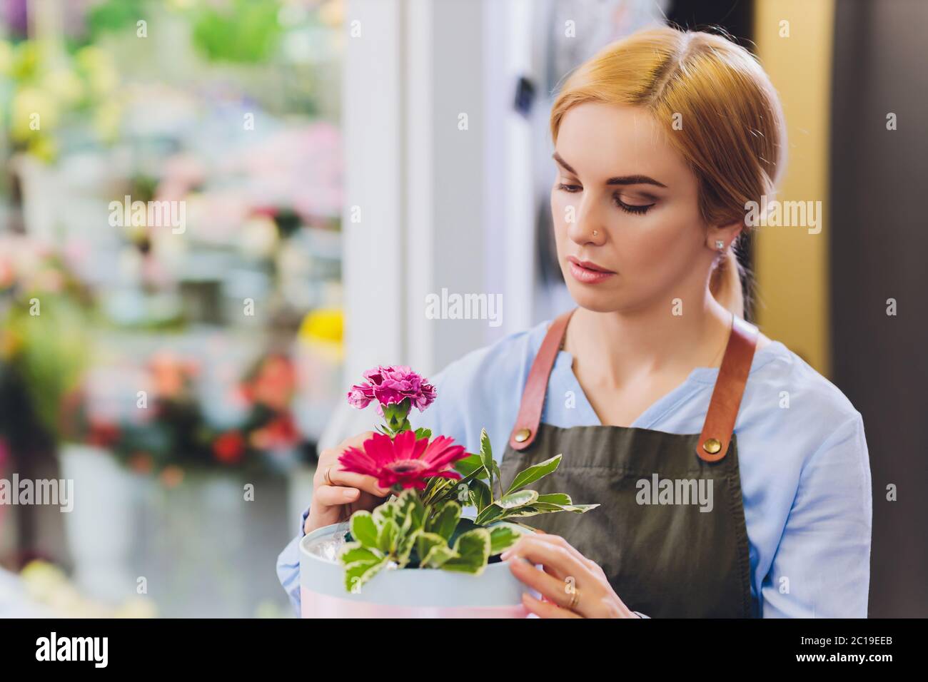 Female sales assistant working as florist and holding bouquet with ...
