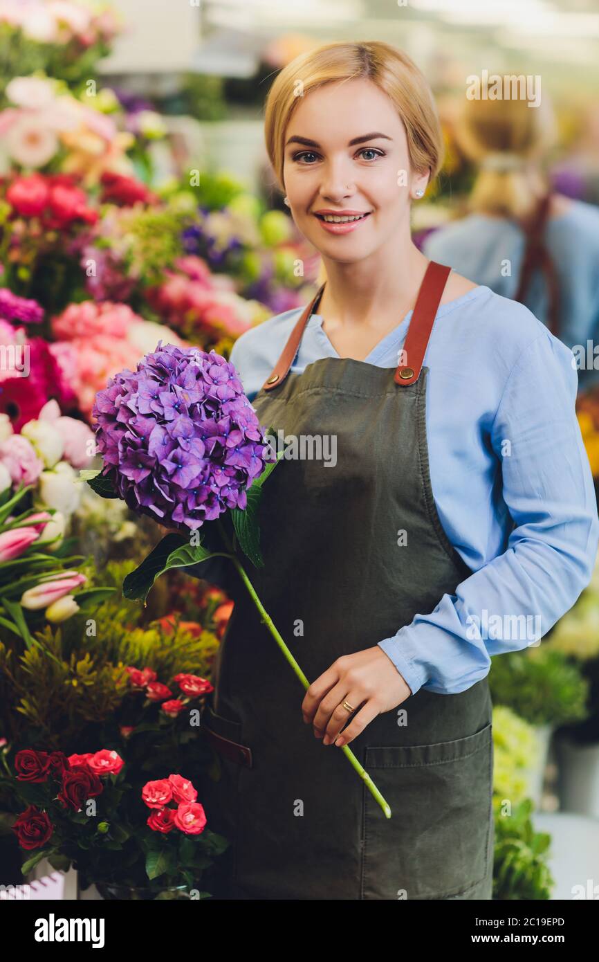 Female sales assistant working as florist and holding bouquet with ...