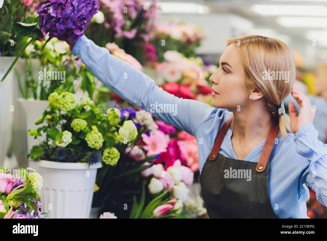 Female sales assistant working as florist and holding bouquet with ...