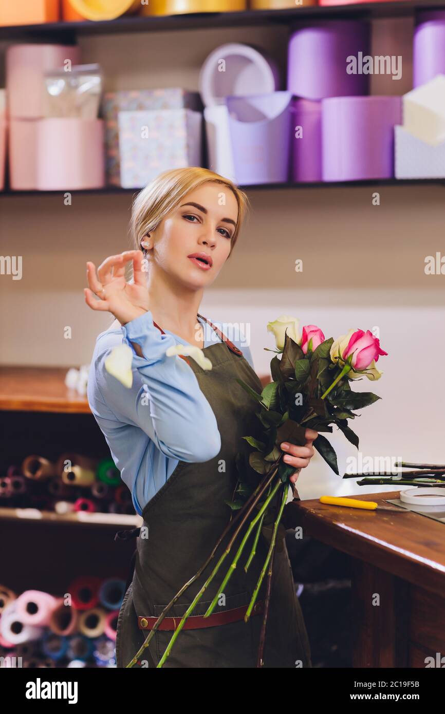 Female sales assistant working as florist and holding bouquet with ...