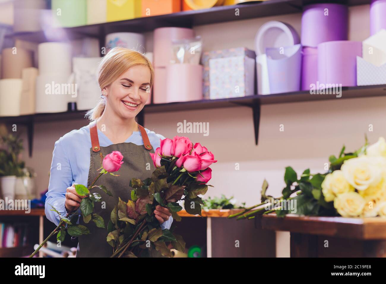 Female sales assistant working as florist and holding bouquet with ...
