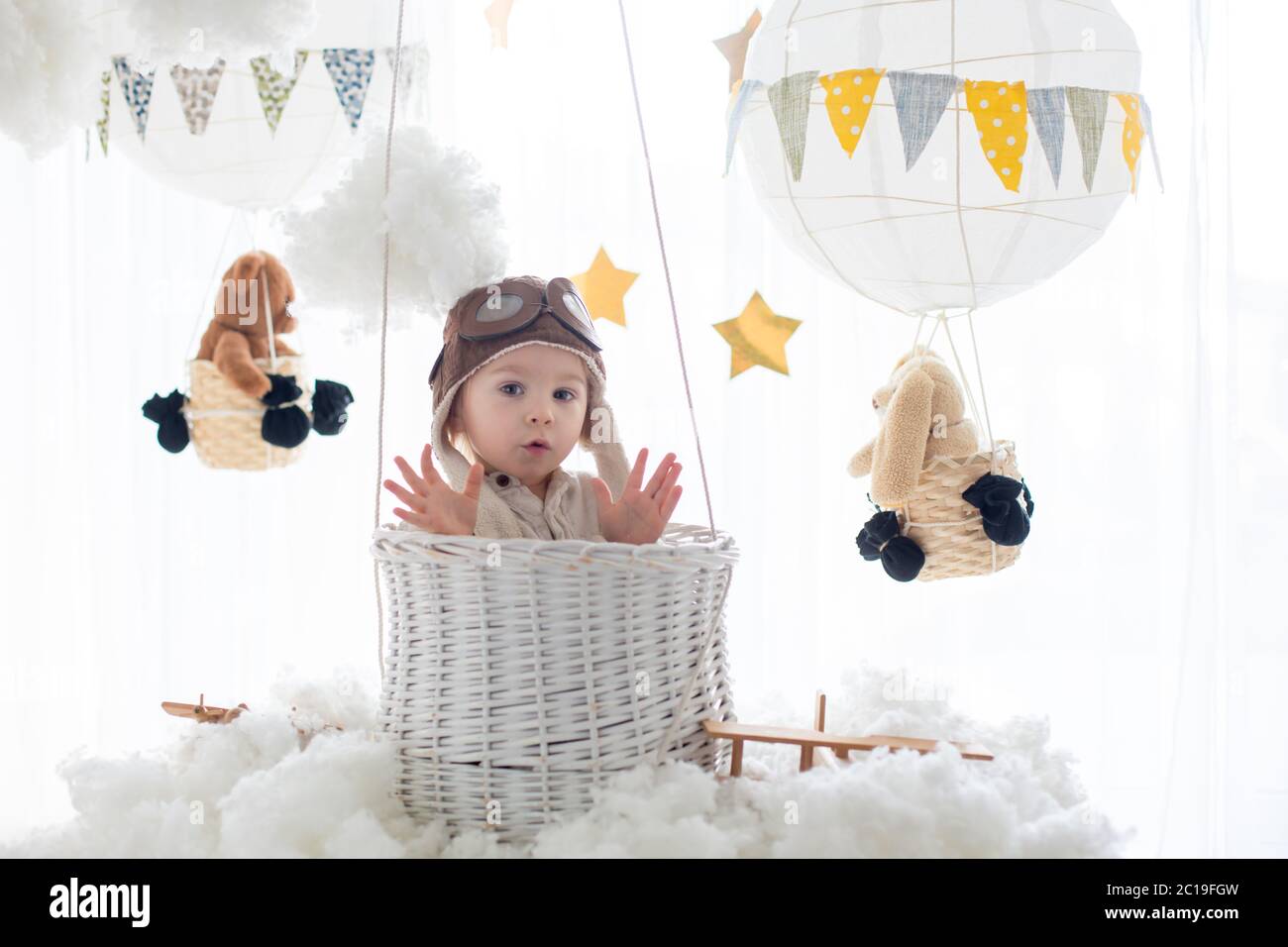 Sweet toddler boy, playing with airplane and teddy bear, decorated air ...